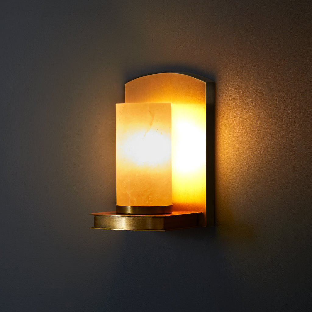 Roly wall sconce in antiqued brass with an alabaster tube